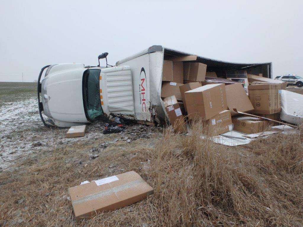 Box truck catches wind, overturns, spills cargo in wheat field